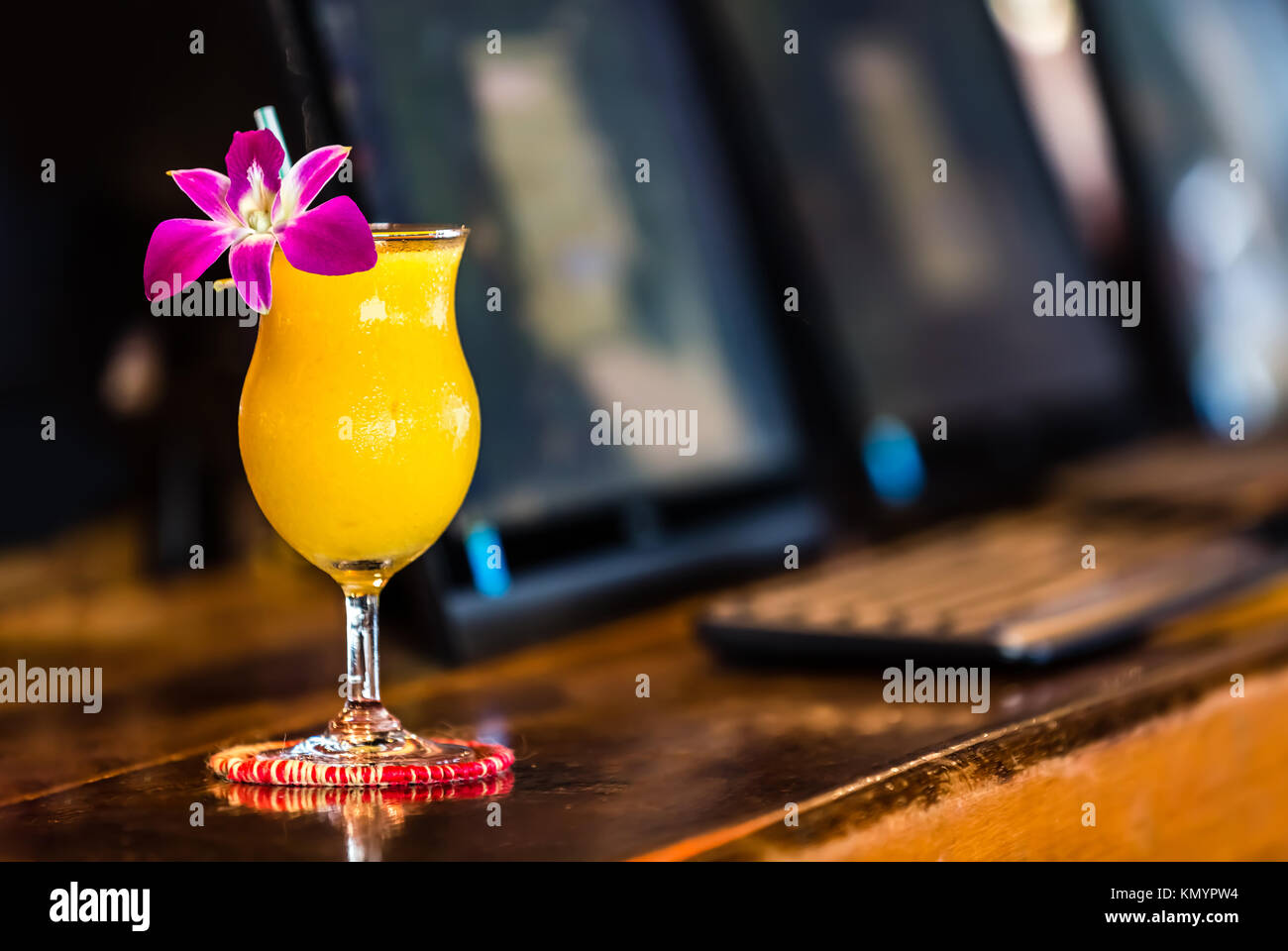 Yellow cocktail with orchid flower in the bar on the blurred background ...