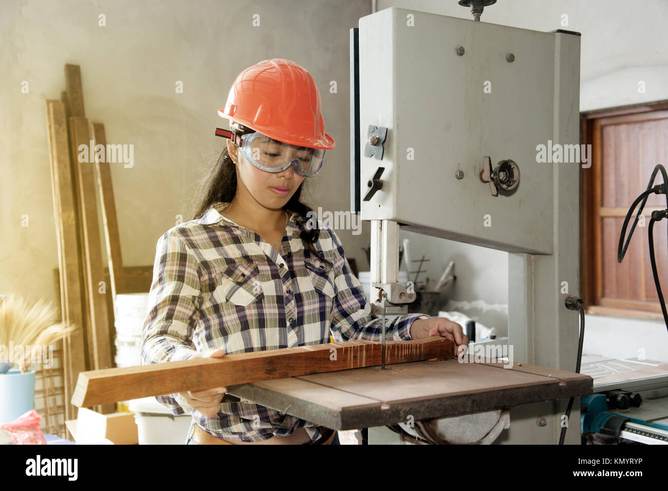 Pretty Asian female carpenter using Electric Sander cut a wood Stock ...