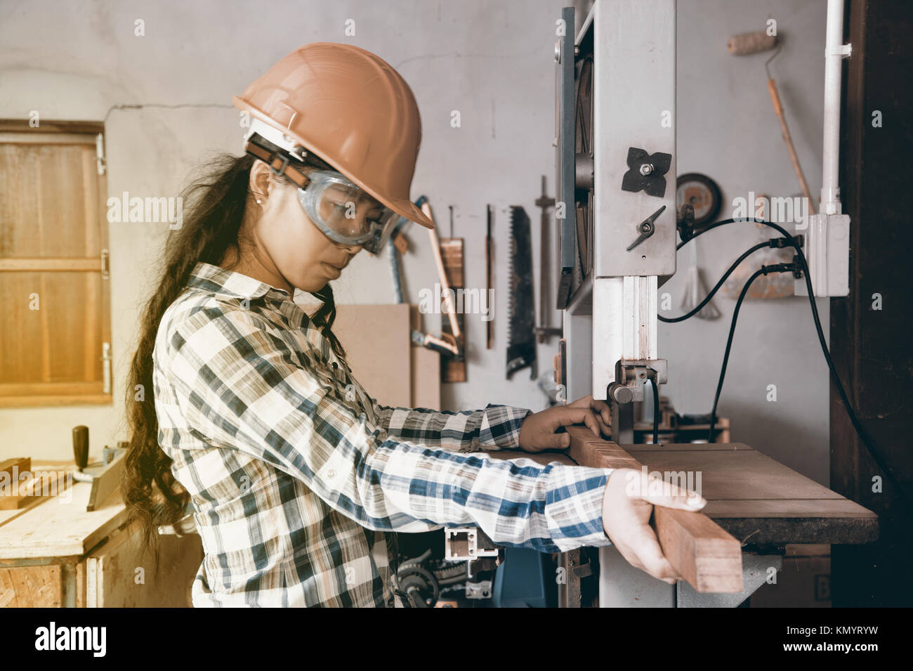 Pretty Asian female carpenter using Electric Sander cut a wood Stock ...