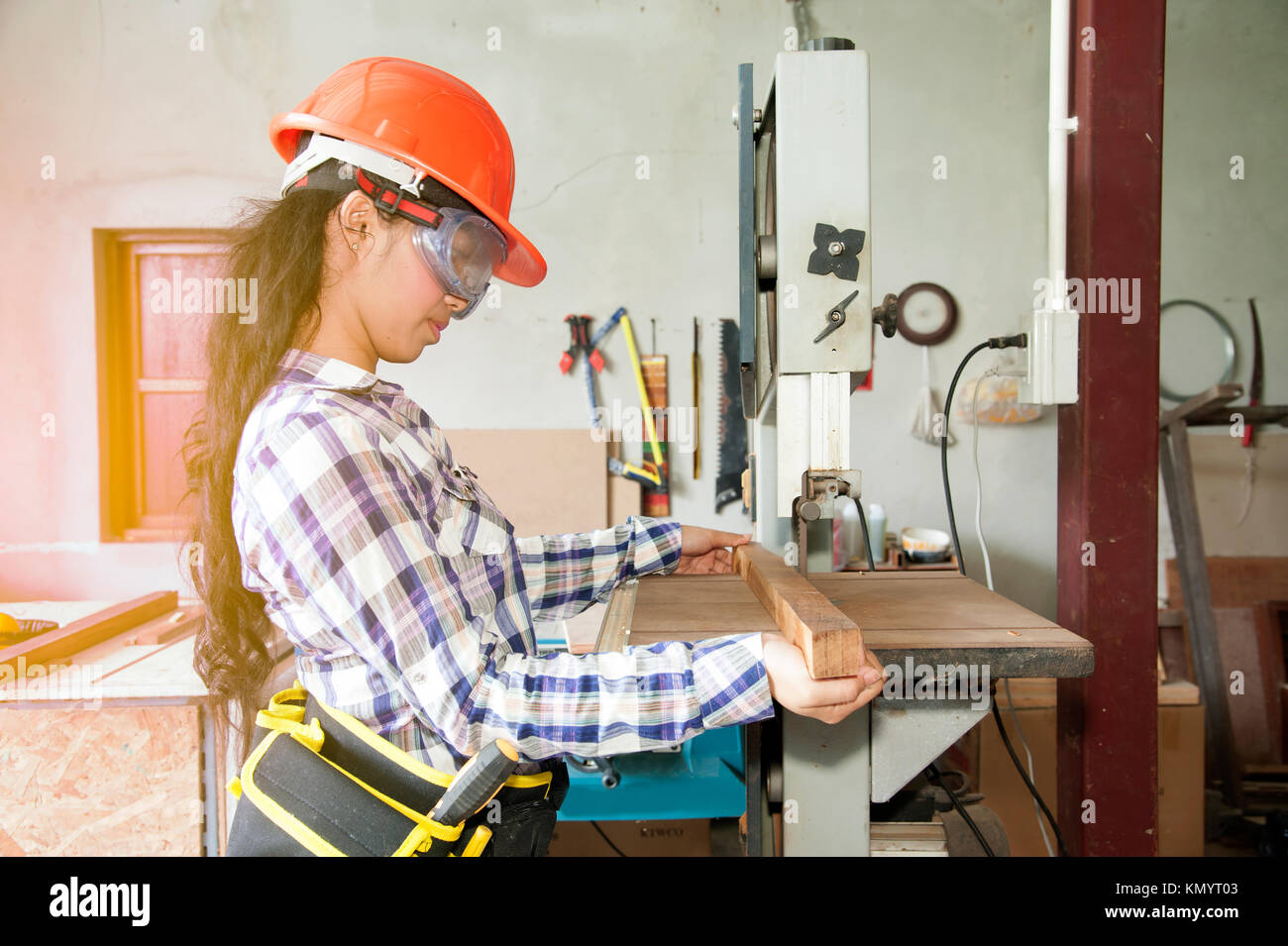 Pretty Asian female carpenter using Electric Sander cut a wood Stock ...