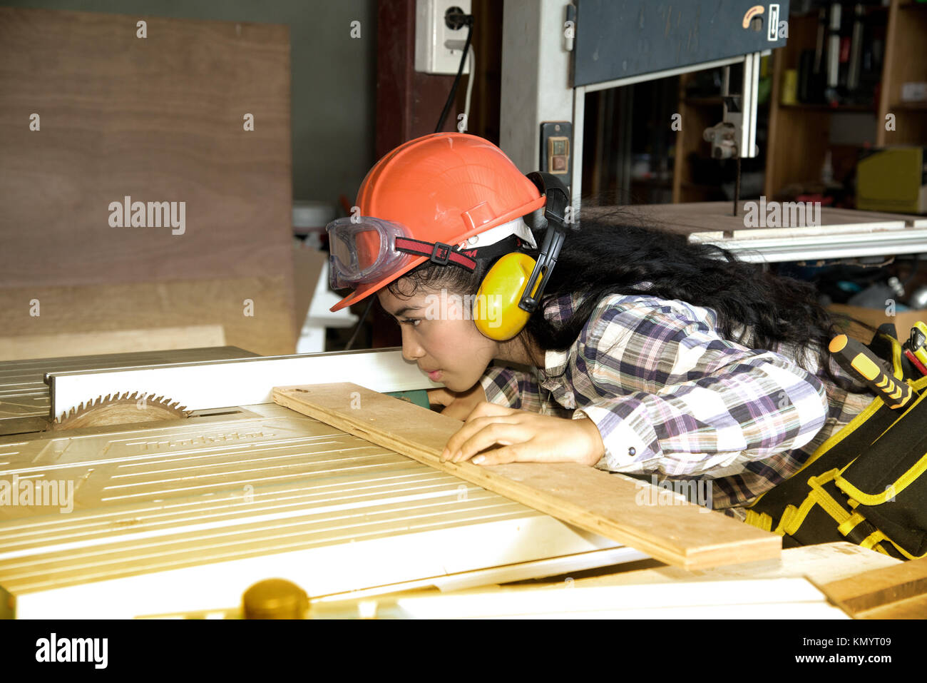 Pretty Asian female carpenter using Electric Sander cut a wood Stock ...