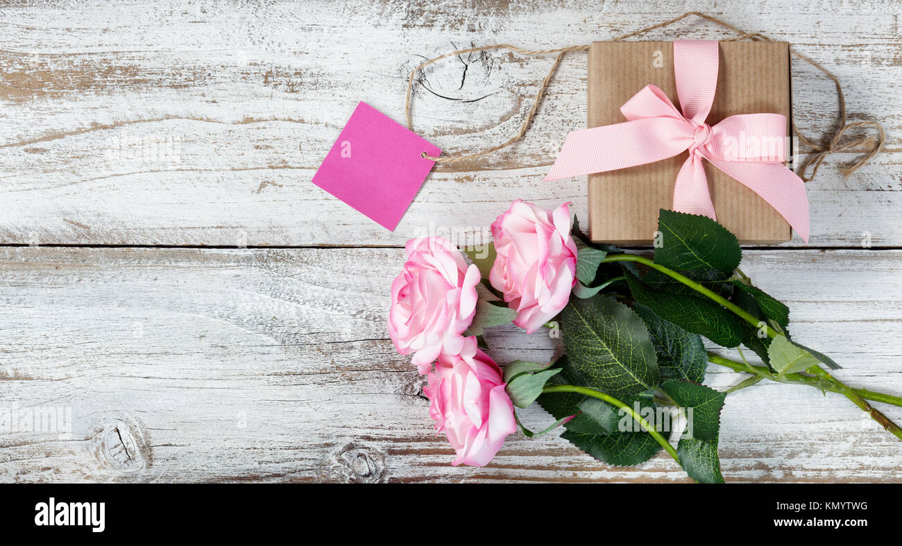Pink roses and gift box for romantic celebrations on rustic white wood ...
