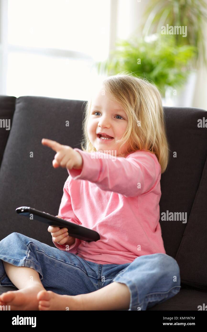 Young girl using remote control in the living room Stock Photo - Alamy