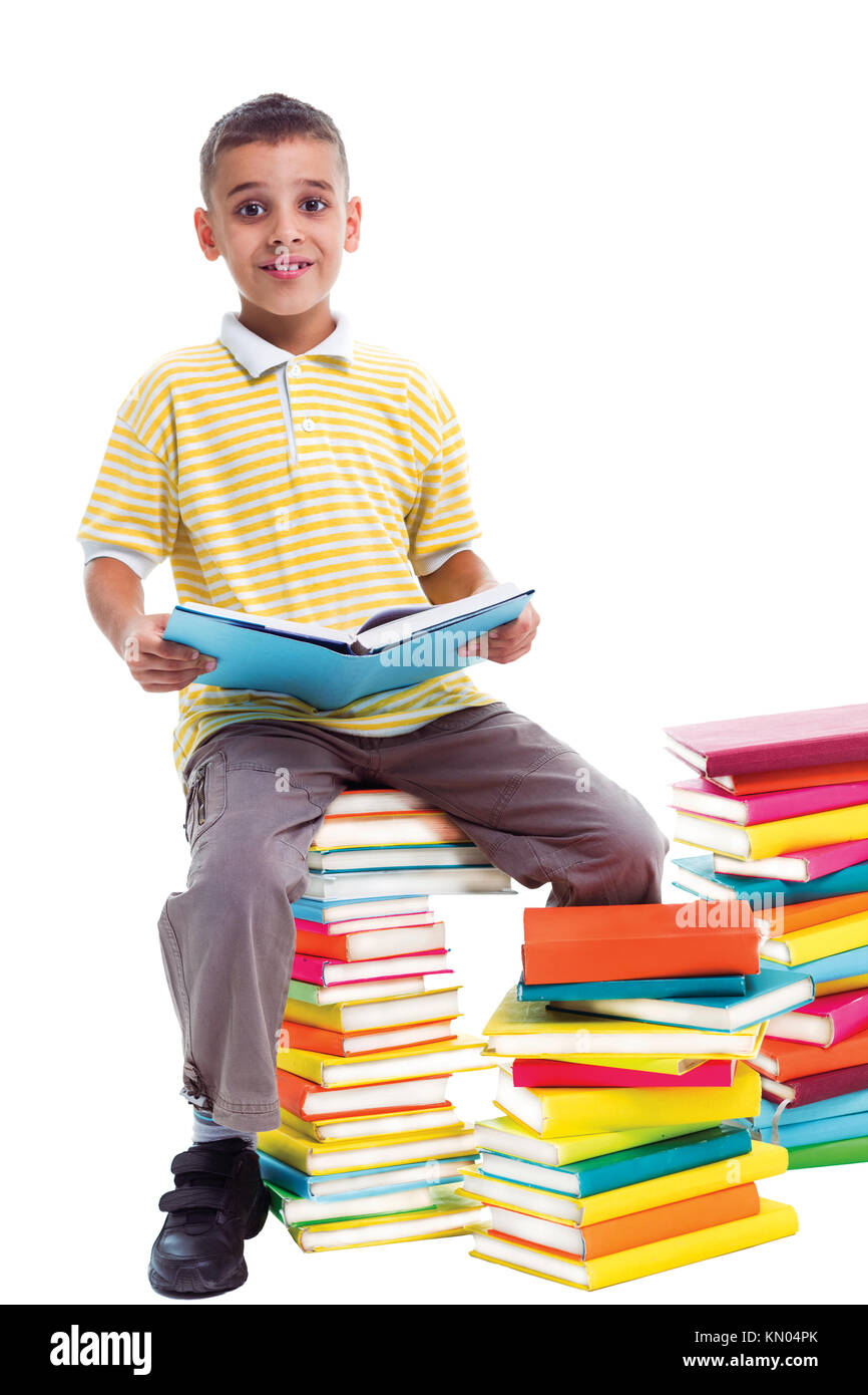 boy sitting on a pile of books and holding one book in his hands Stock ...