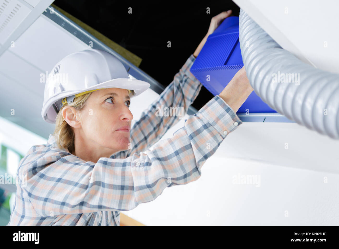 female worker fitting ventilation system in buildings ceiling Stock ...
