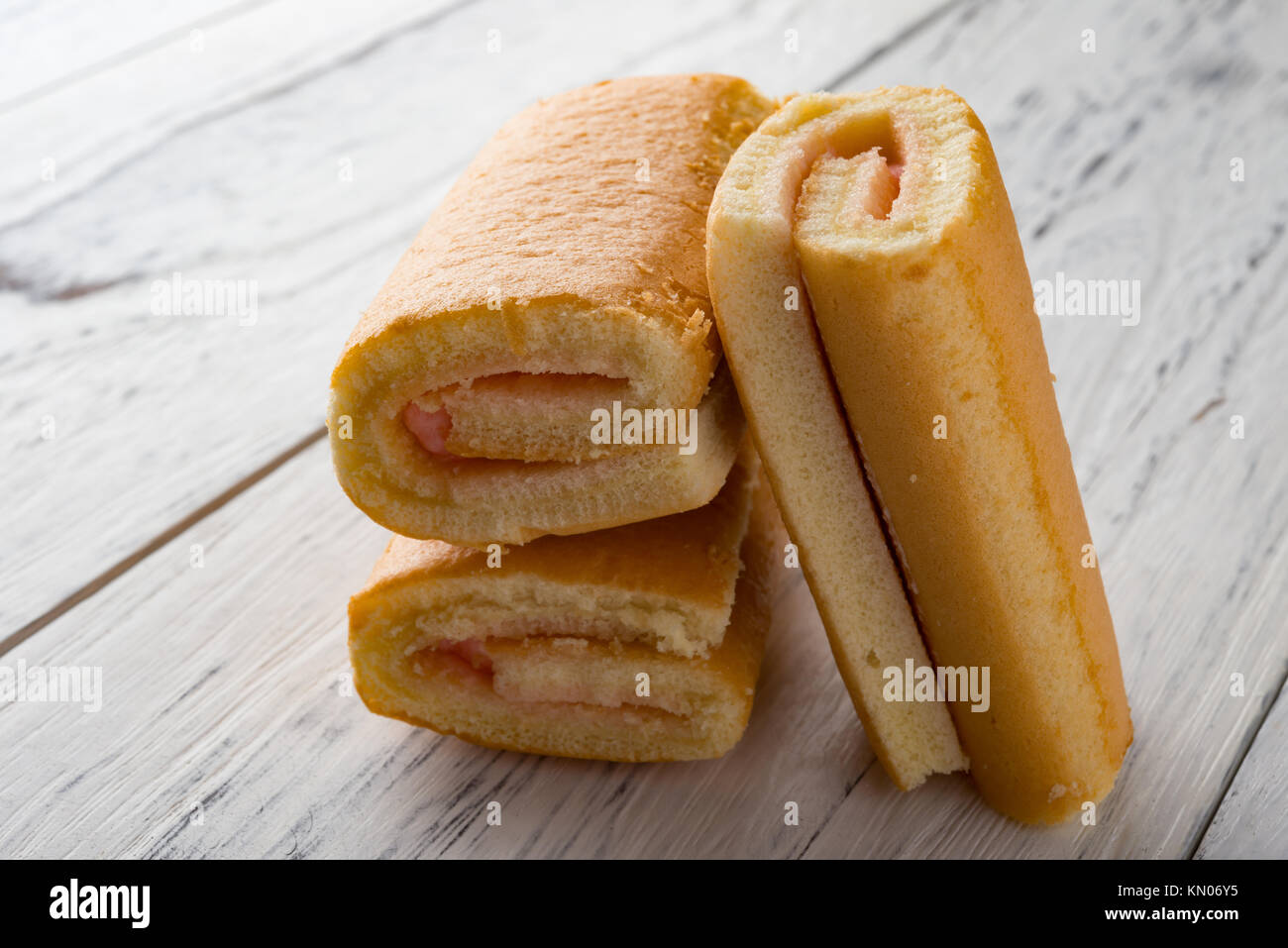 three strawberry flavor sweet rolls on white wood Stock Photo - Alamy