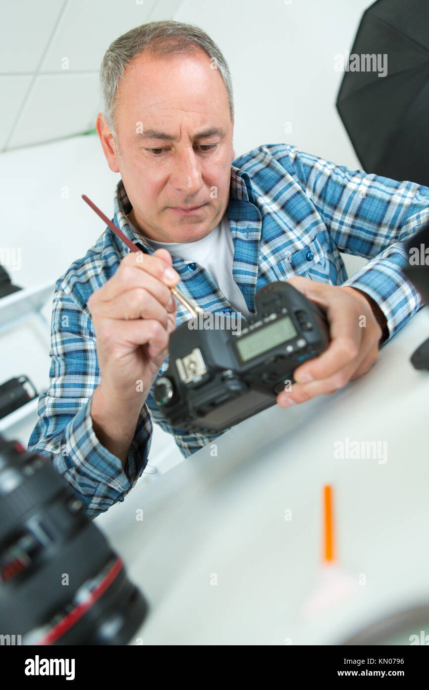 man cleaning digital camera body using a brush Stock Photo - Alamy