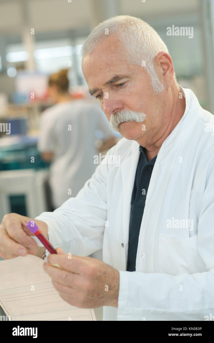 senior male laboratory worker labelling vial of blood Stock Photo - Alamy