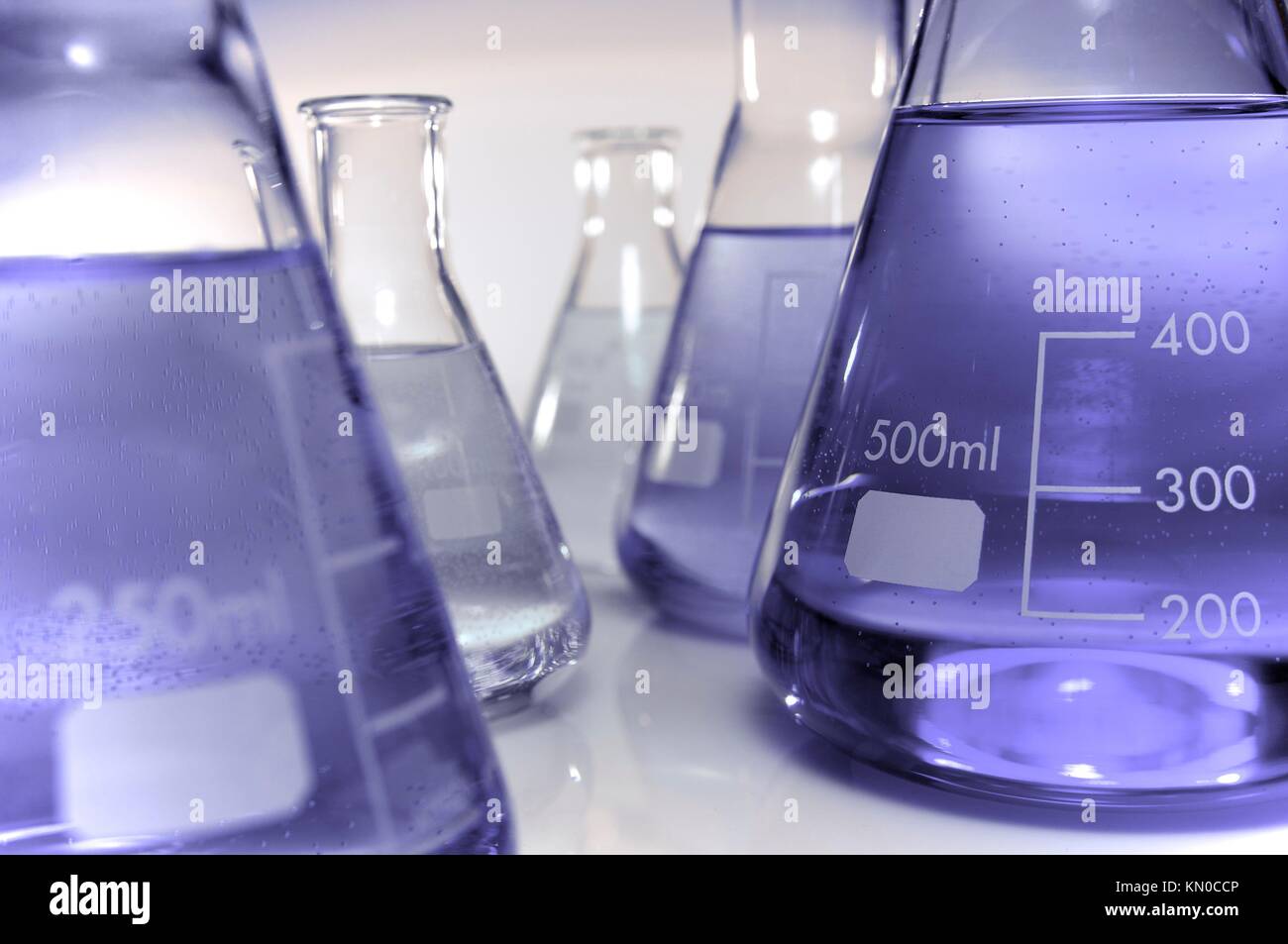 forefront of a group of purple liquid conical flasks Stock Photo - Alamy