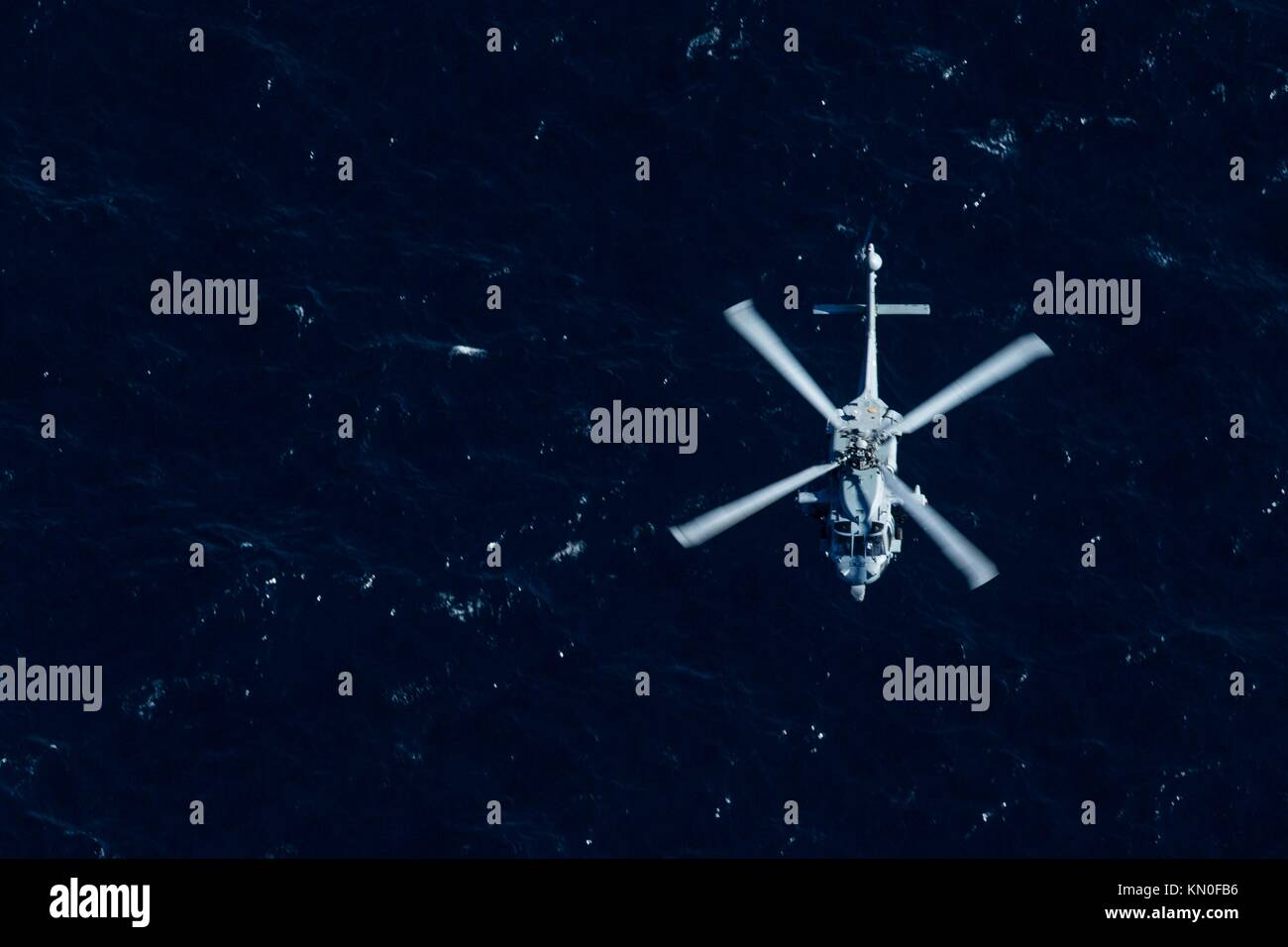 A U.S. Navy MH-60S Seahawk helicopter flies over the ocean during a ...