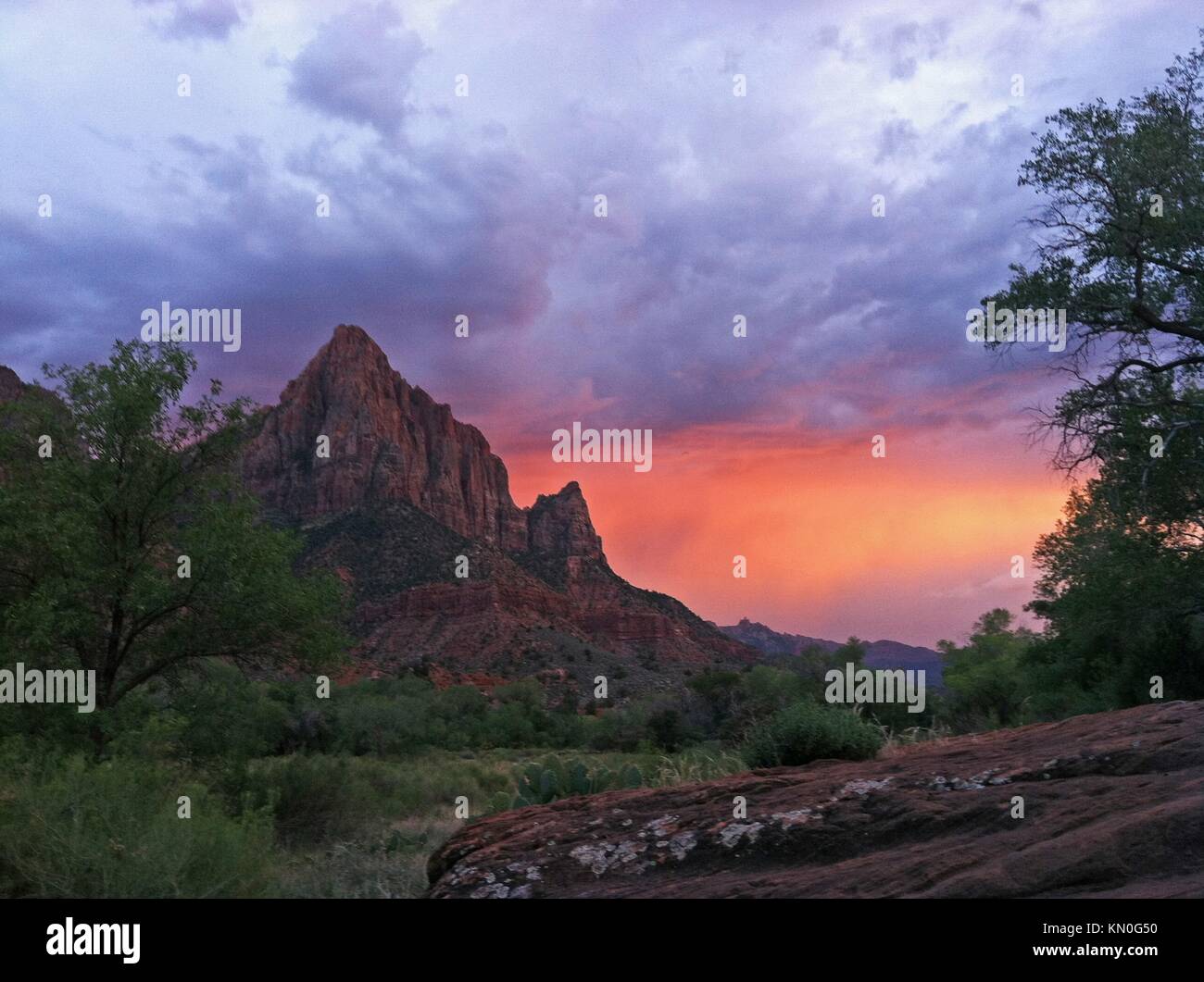 A storm forms in the sky as the sun sets over the Watchman rock ...