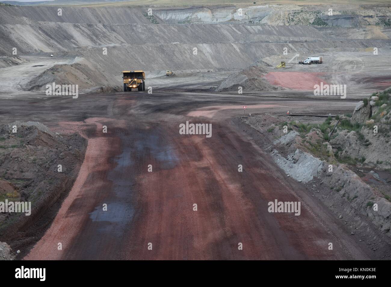 Massive coal mining vehicle driving on a road inside a vast open pit ...