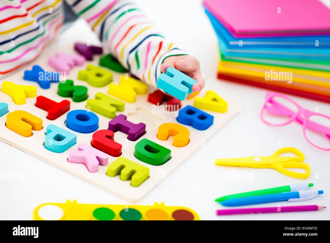 Child doing homework for school at white desk. Wooden educational abc ...