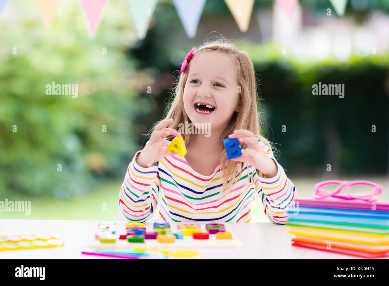 Child doing homework for school at white desk. Wooden educational abc ...