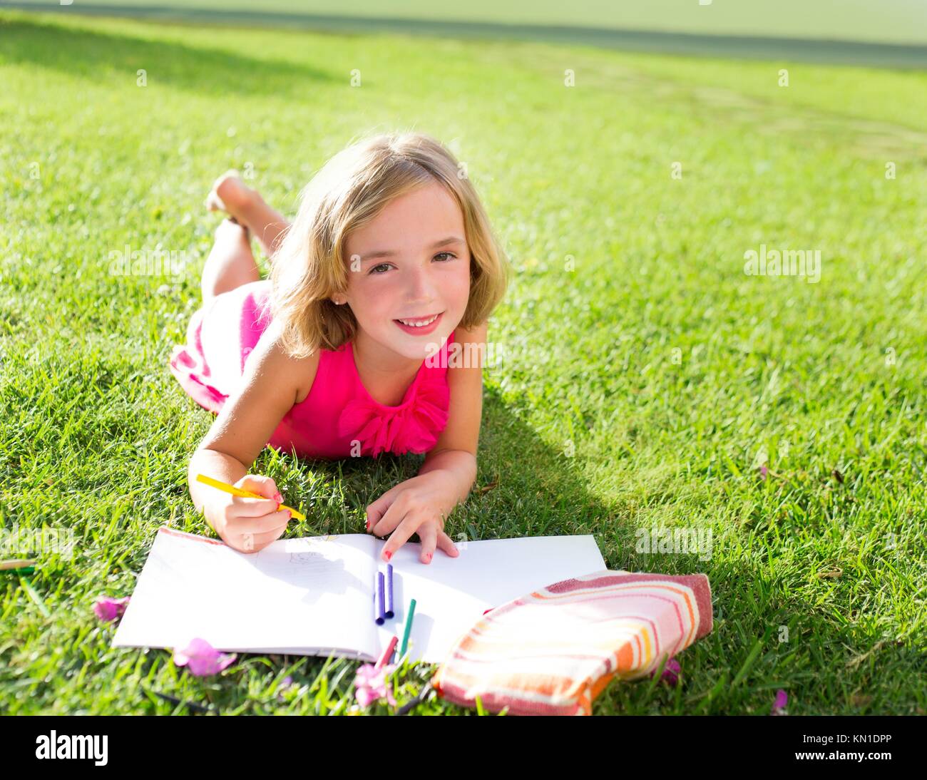child kid girl doing homework smiling happy lying on grass garden with ...