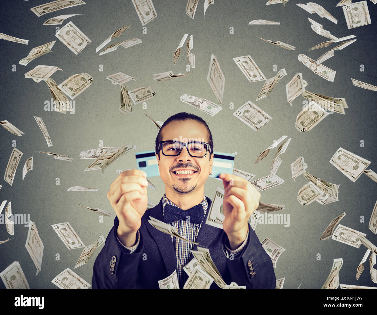 Happy debt free man holding a credit card cut in two pieces under money ...