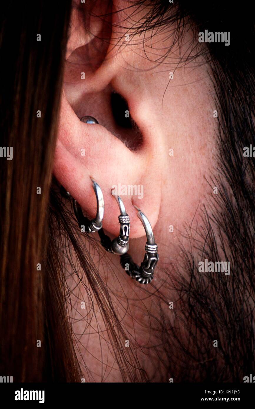 Close view of an ear with three ear-rings Stock Photo - Alamy