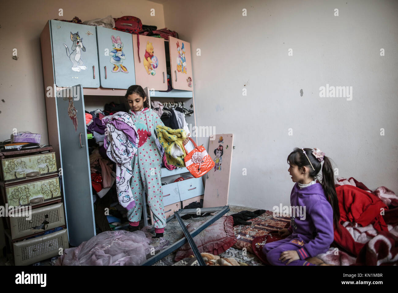 Palestinian girls salvage clothes from their home which was damaged ...