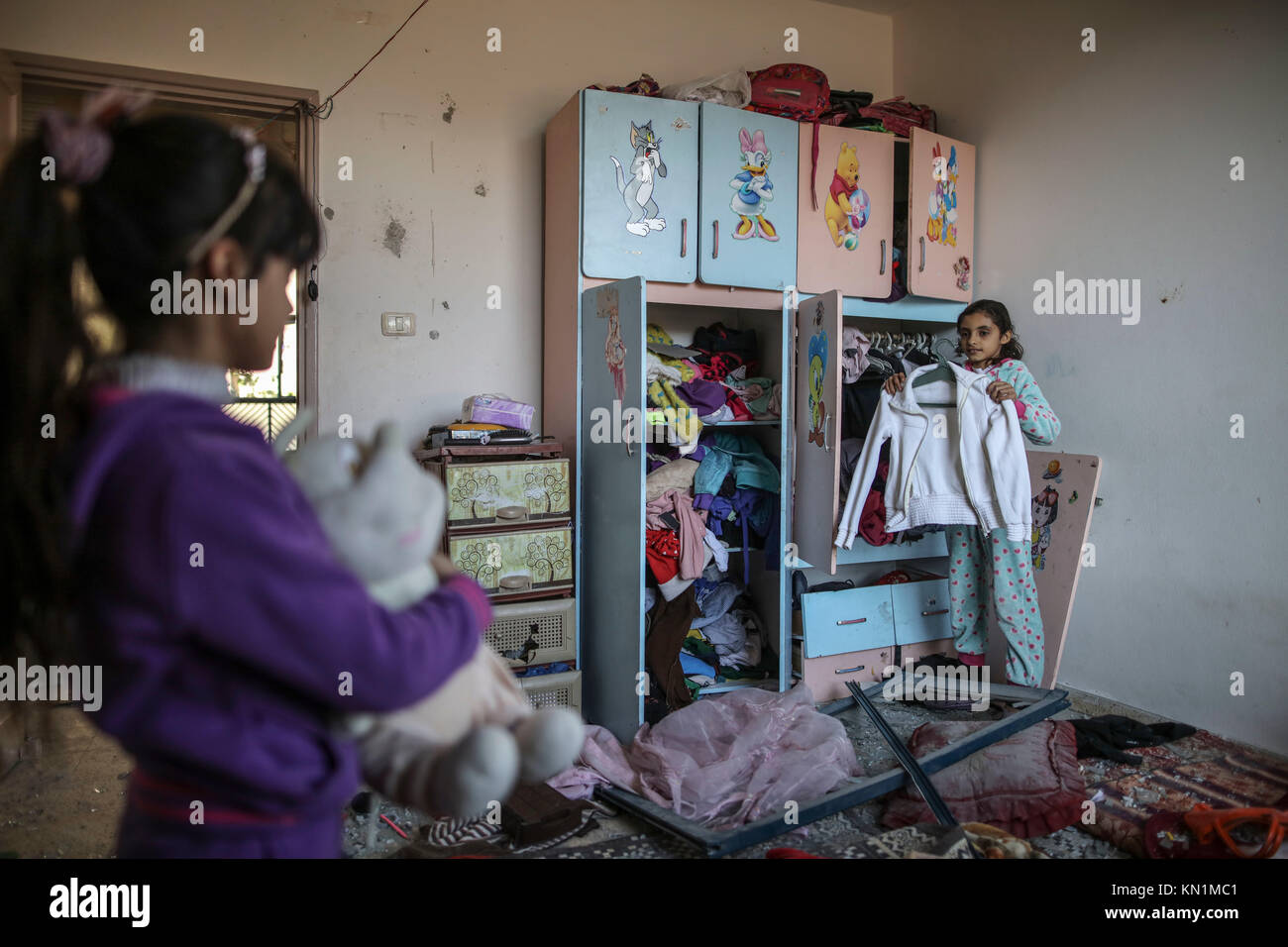 Palestinian girls salvage clothes from their home which was damaged ...