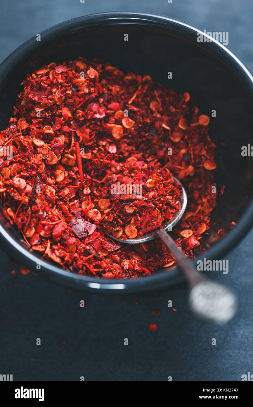 Top view of the black bowl with chili spices on the textured blue table ...