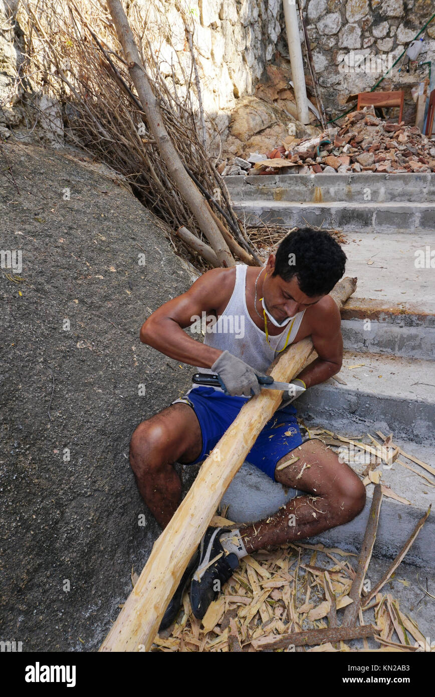 Mexican man scraping bark fron tree limbs to make stair railings ...