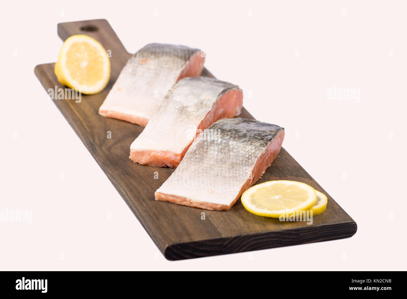 Frozen salmon fish fillets with lemon slices isolated on wood board ...