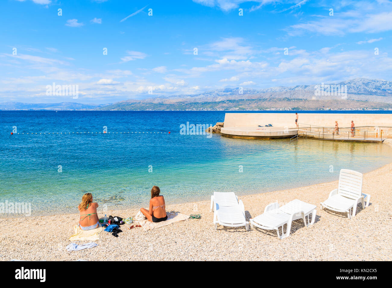 Two unidentified young women relaxing on beautiful beach in Postira ...