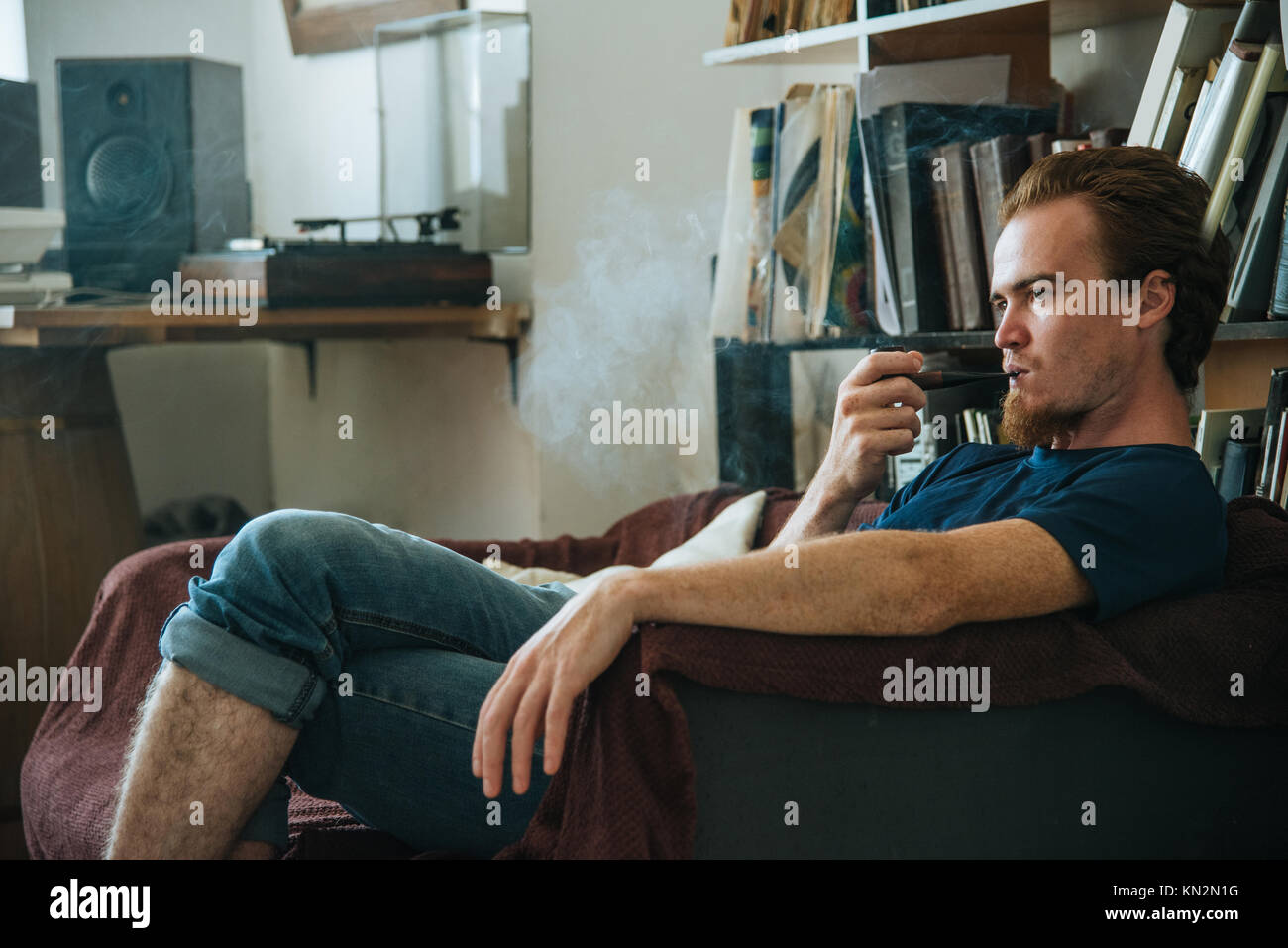 Smiling young man smoke pipe, listen old music and enjoy his life Stock ...