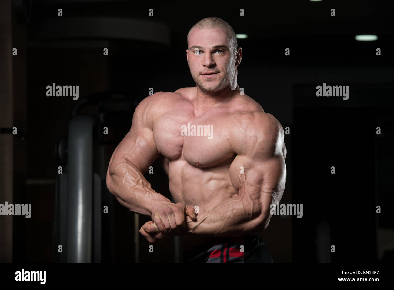 Healthy Young Man Standing Strong In The Gym And Flexing Muscles ...
