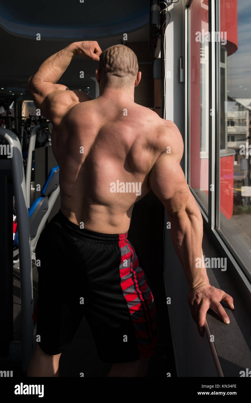 Handsome Young Man Standing Strong In The Gym And Flexing Muscles ...