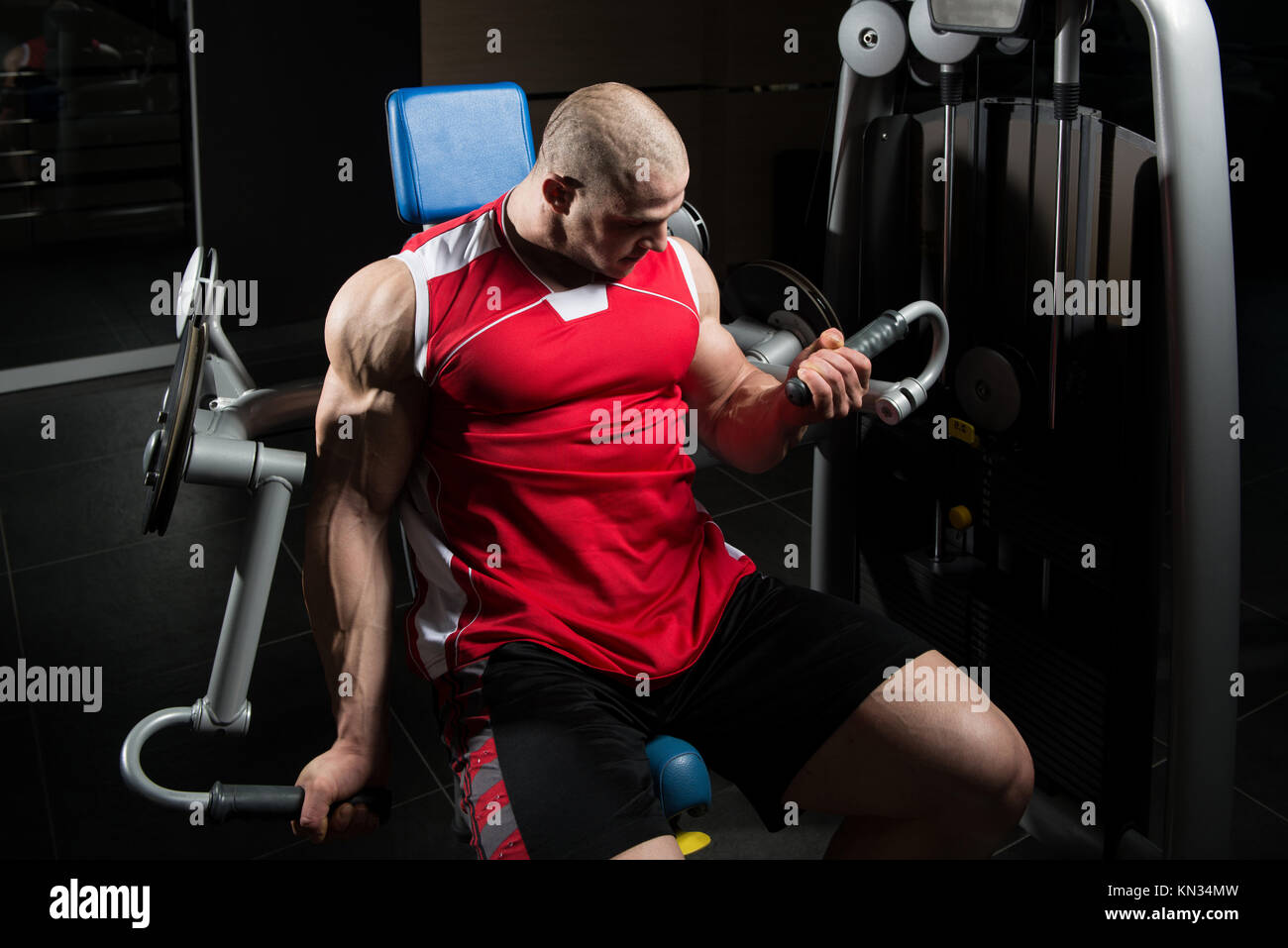 Man In The Gym Exercising On His Biceps On Machine With Cable In The ...