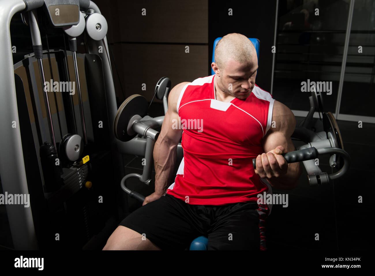 Man In The Gym Exercising On His Biceps On Machine With Cable In The ...