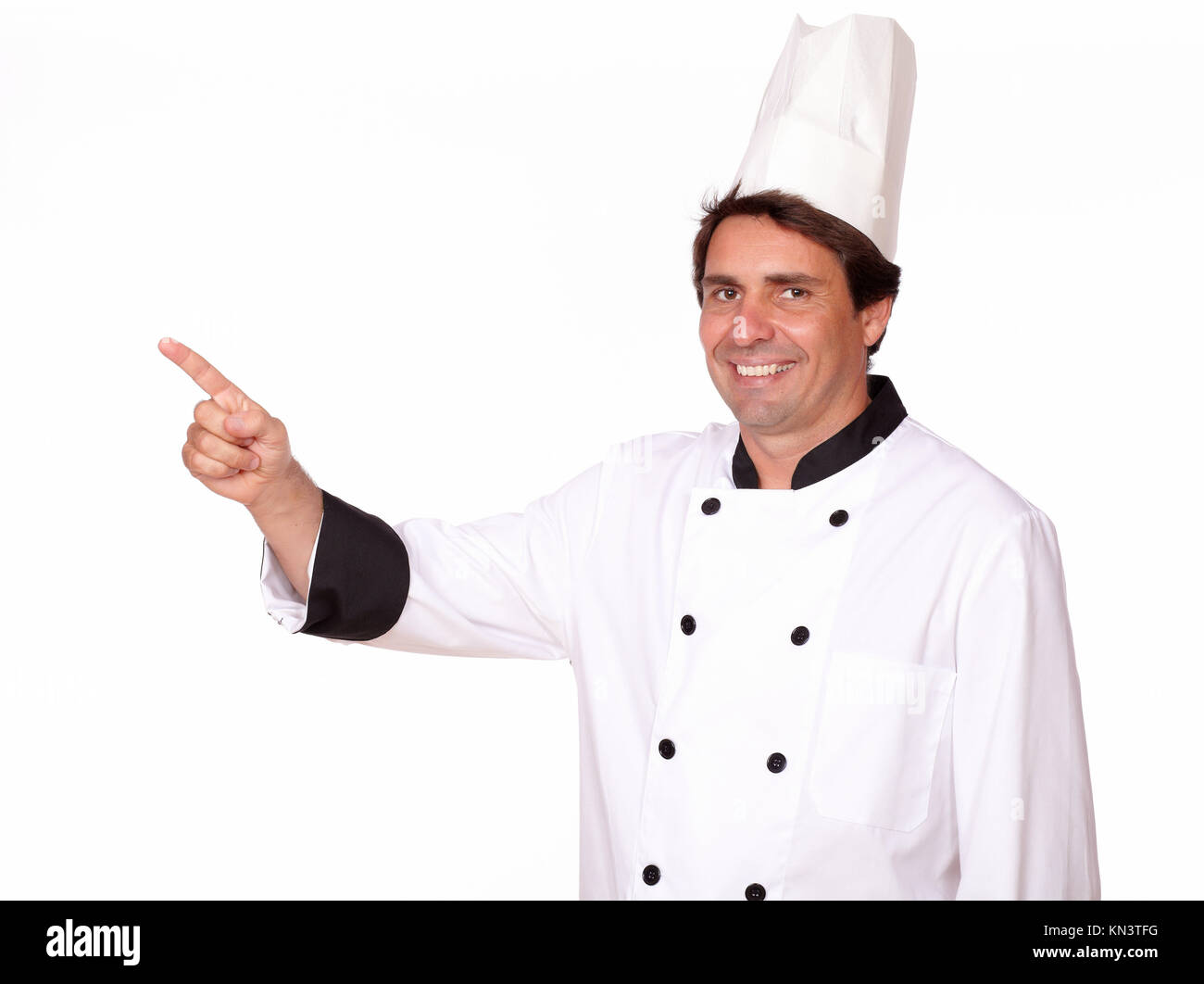 Portrait of a charming chef pointing to his right while is smiling on ...