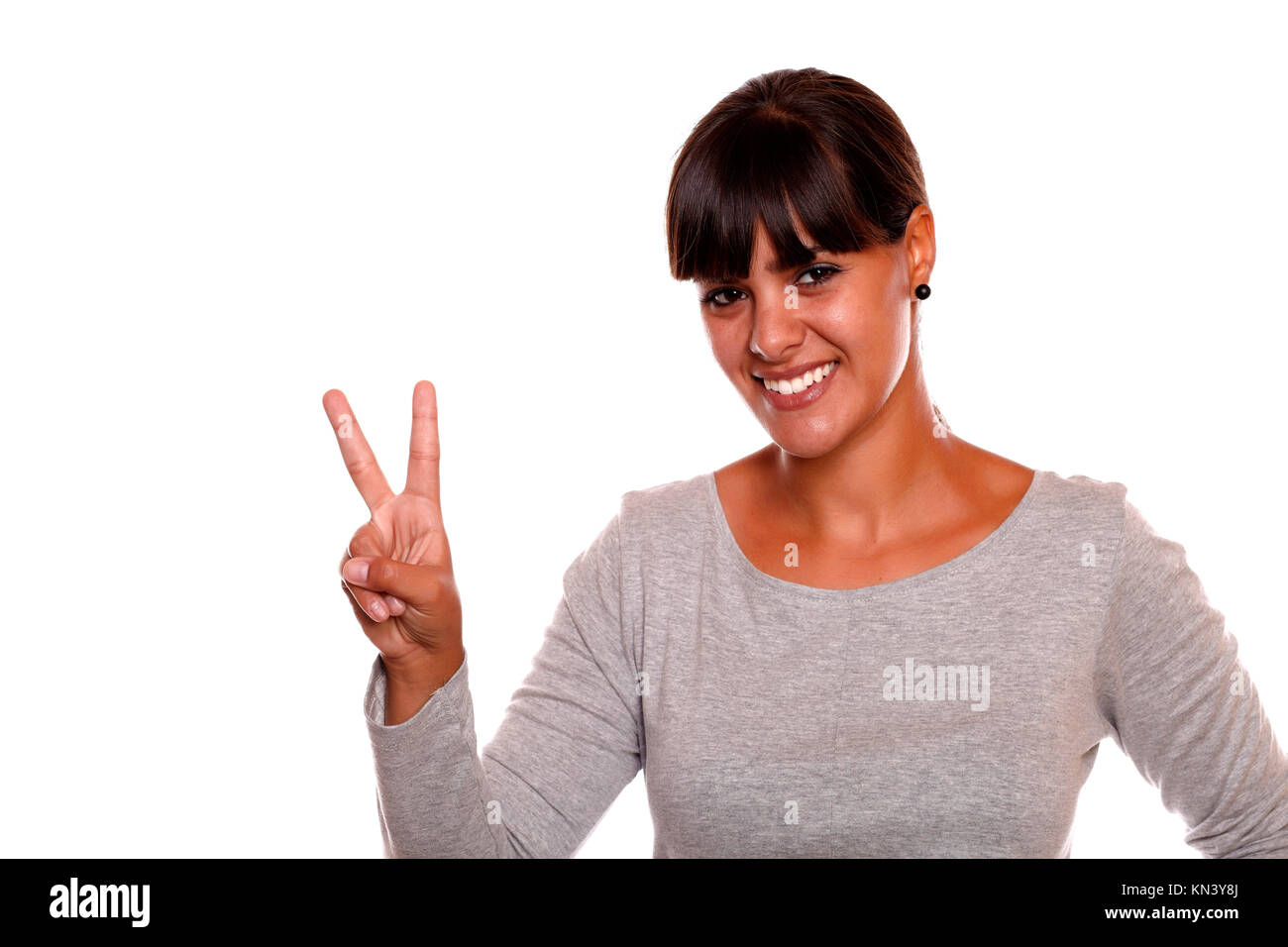 Pretty girl holding up two fingers in victory sign on grey dress ...