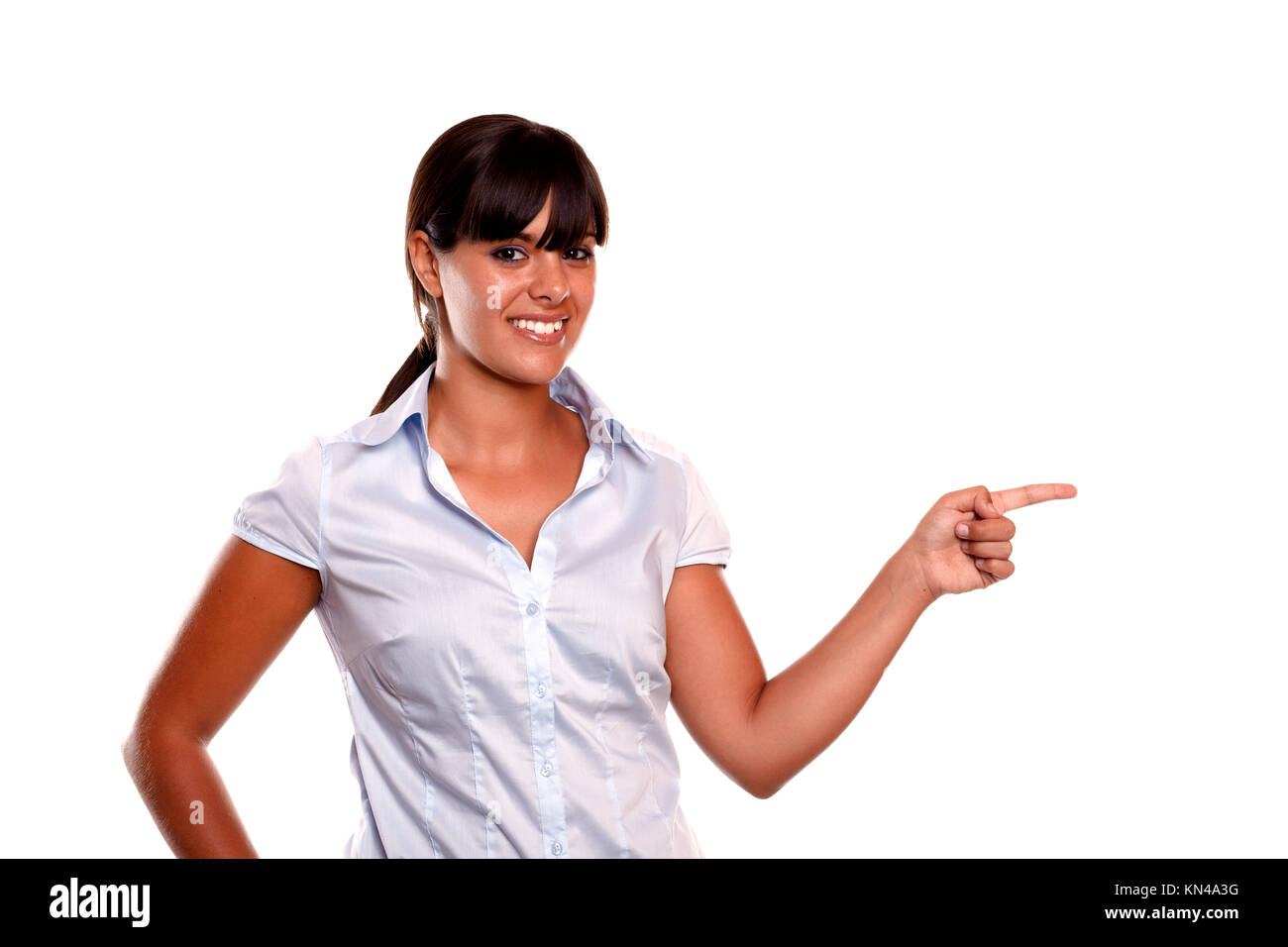 Charming young woman smiling and looking at you while pointing left ...