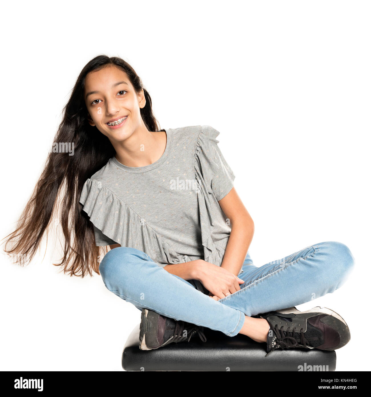 brunette teen girl sits on piano stool against white background Stock ...