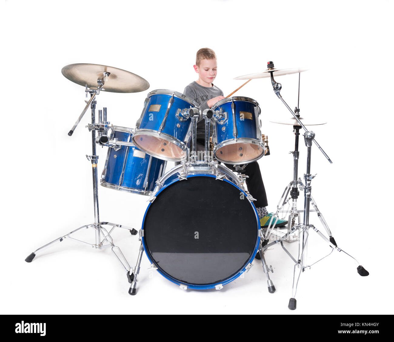 yount blond teen boy at drum kit in studio against white background ...