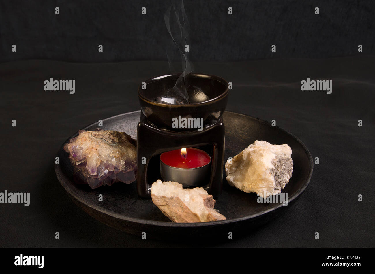 Natural stones on the pot with candle and incense Stock Photo - Alamy