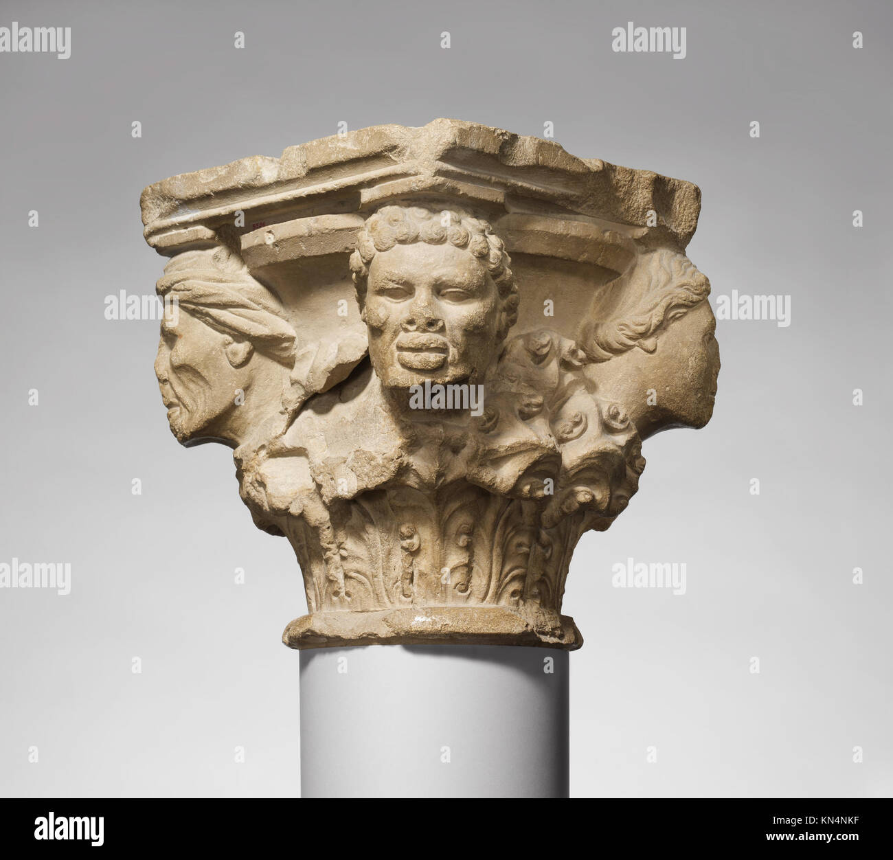 Architectural capital featuring four heads, showing sculptural detail ...