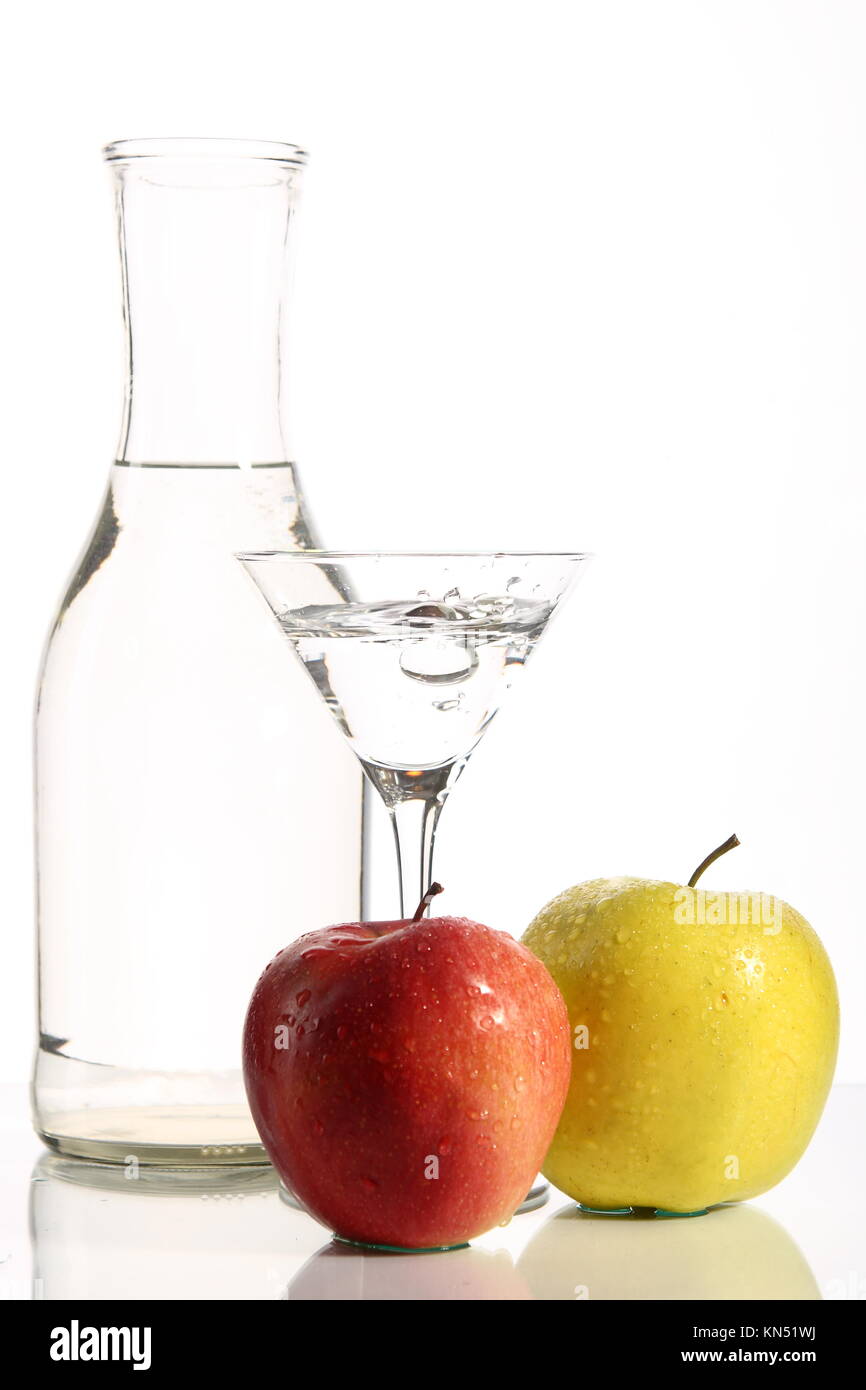 Bottle with transparent water, a glass and apples on a white background ...