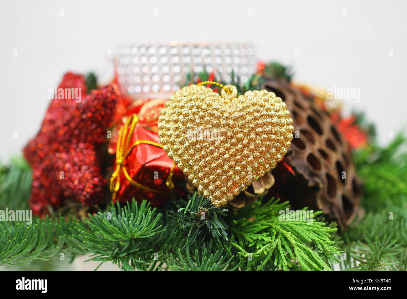 Bauble in shape of heart covered in golden glitter with other Christmas ...