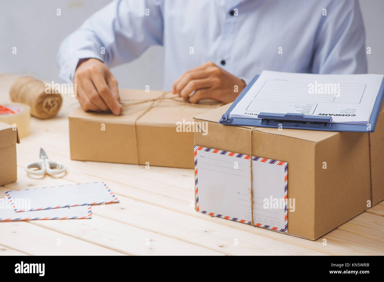 Courier making notes in delivery receipt among parcels at table Stock ...