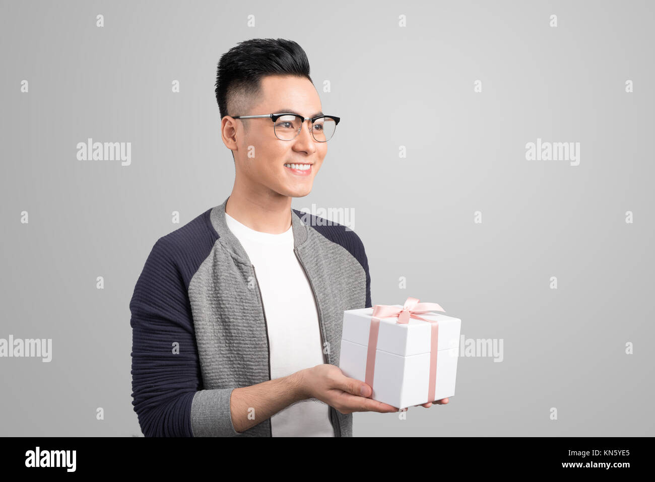 Happy young asian man giving gift box over gray background Stock Photo ...