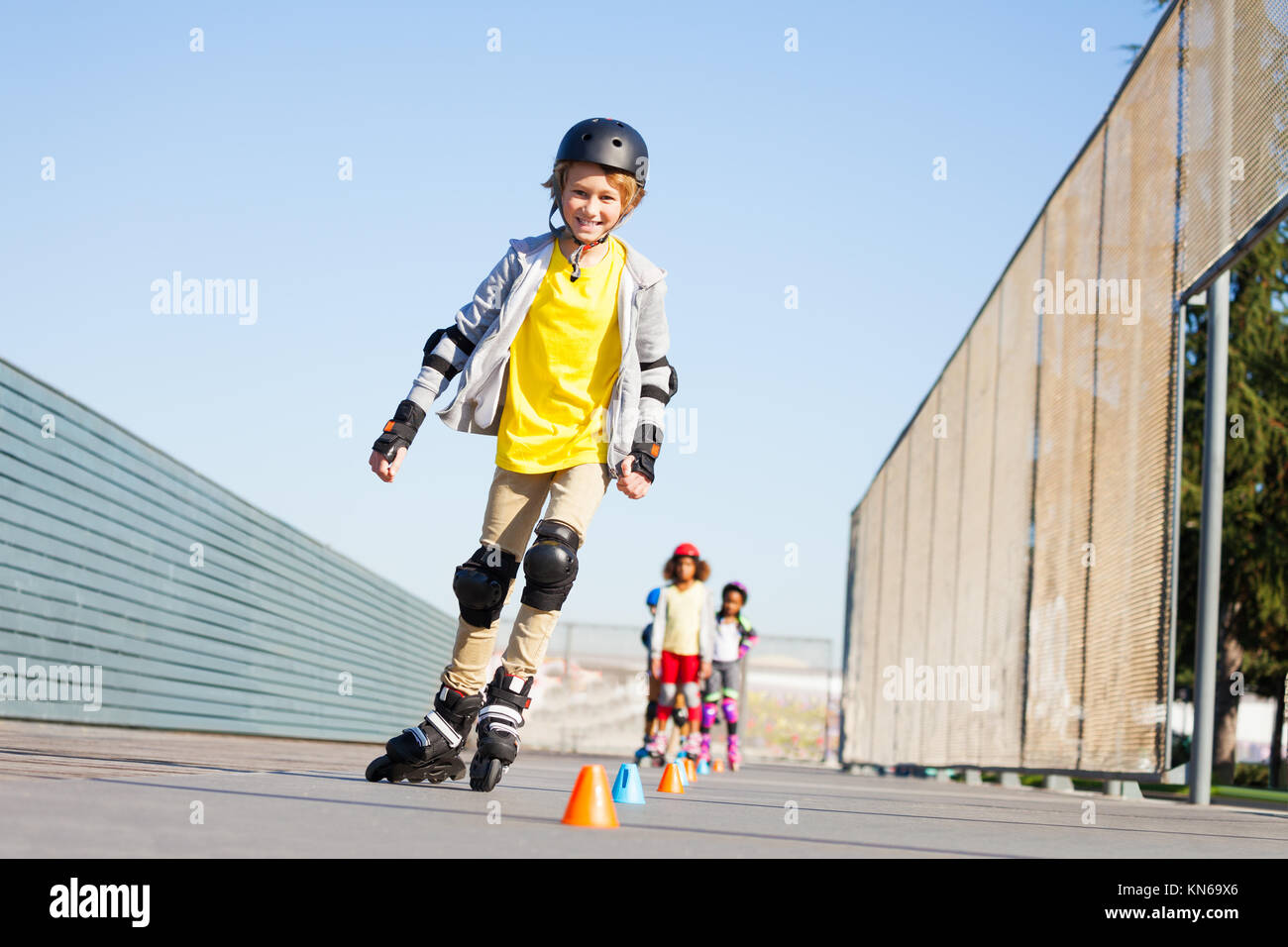 Portrait of preteen boy, happy inline skater, curving around the cones ...