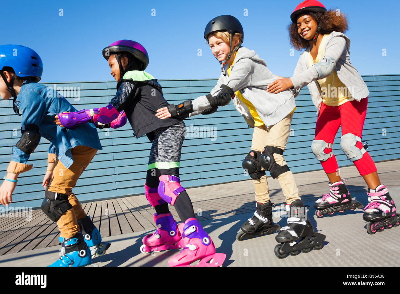 Four happy multiethnic boys and girls having fun while rollerblading ...