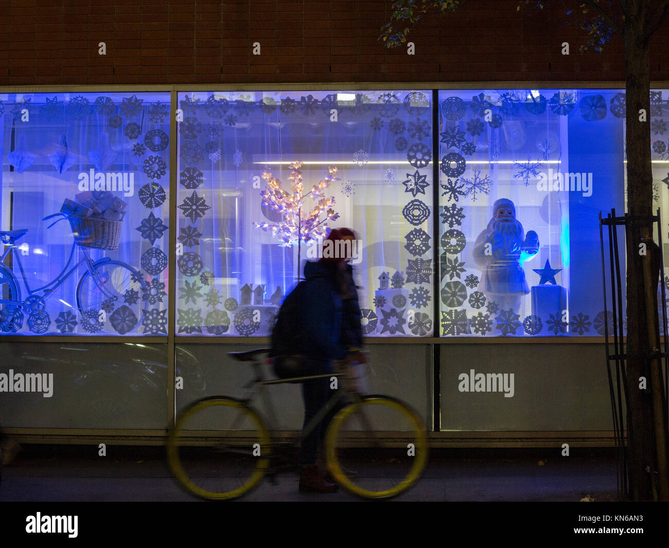 A silhouette of someone looking in to the window of a Christmas display ...