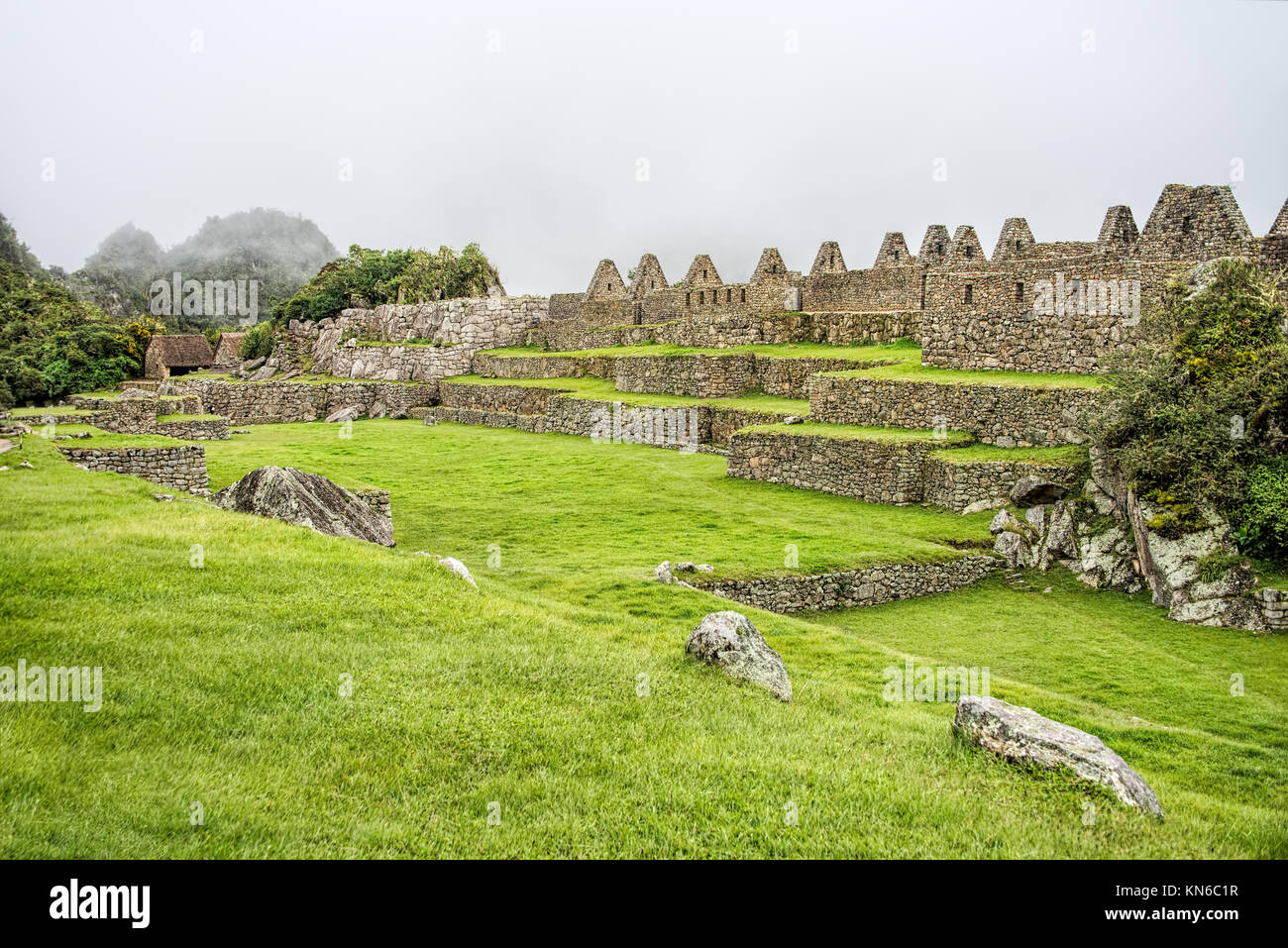 Green fields of ancient Inca Citadel under heavy fog Stock Photo - Alamy