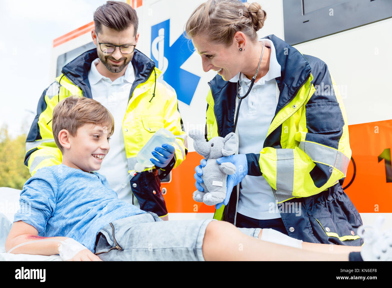 Emergency medic giving soft toy to console injured boy Stock Photo - Alamy