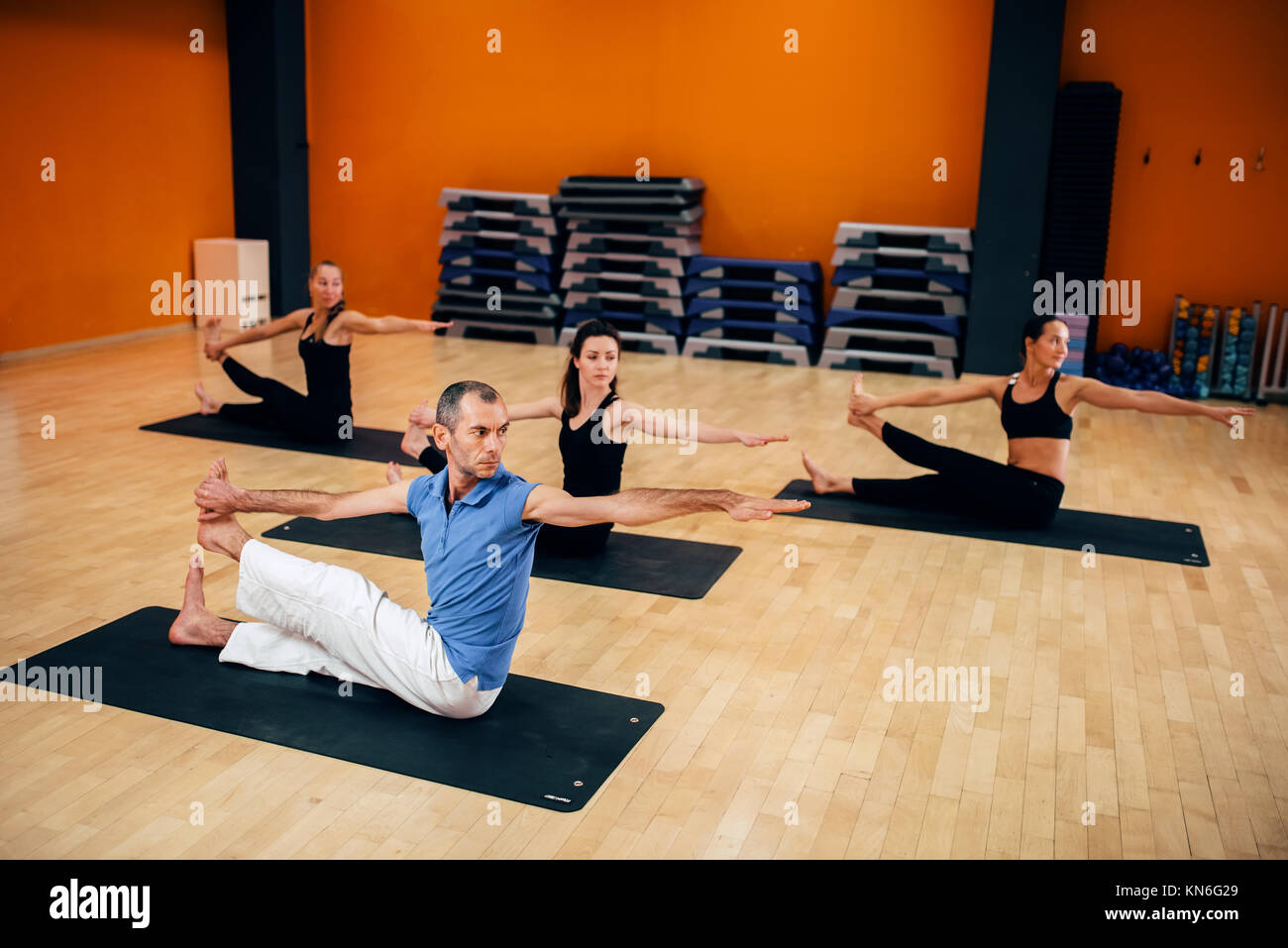 Yoga training, female group workout with male trainer in gym. Yogi ...