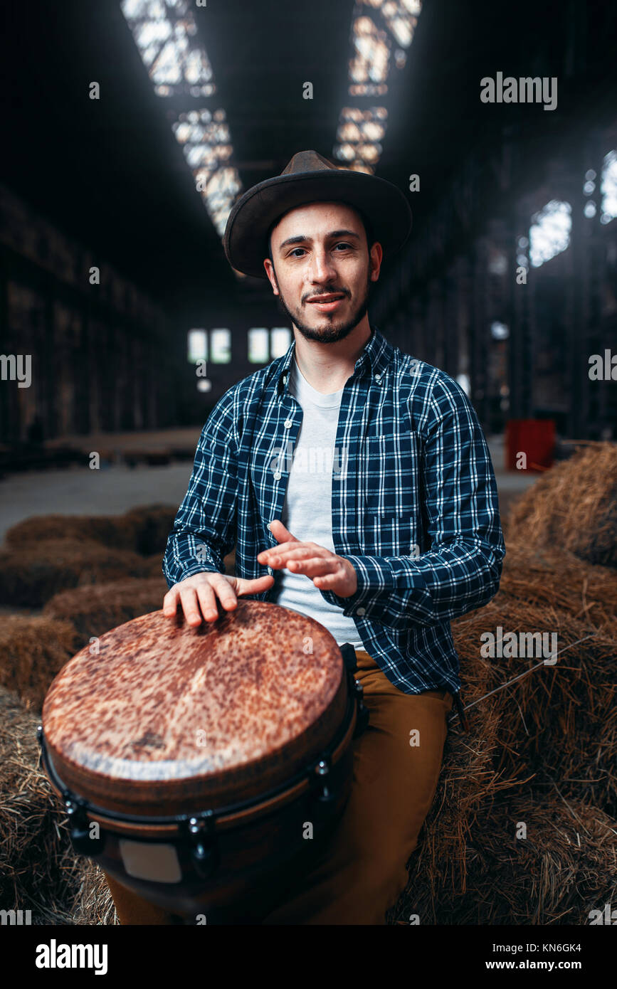 Young male drummer against african wooden drum, factory shop on ...